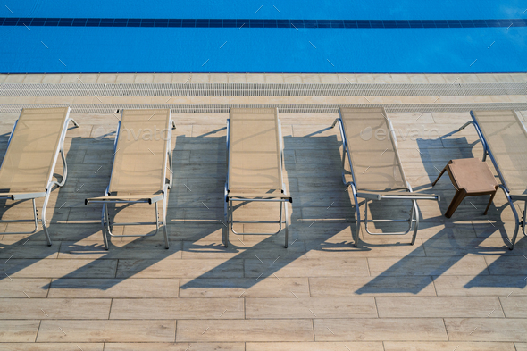 top view row of sunlounger chairs near a outdoor swimming pool with ...
