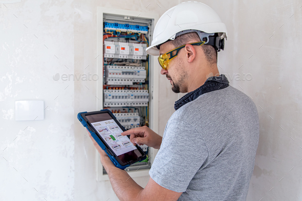 Electrical technician looking focused while working in a switchboard ...
