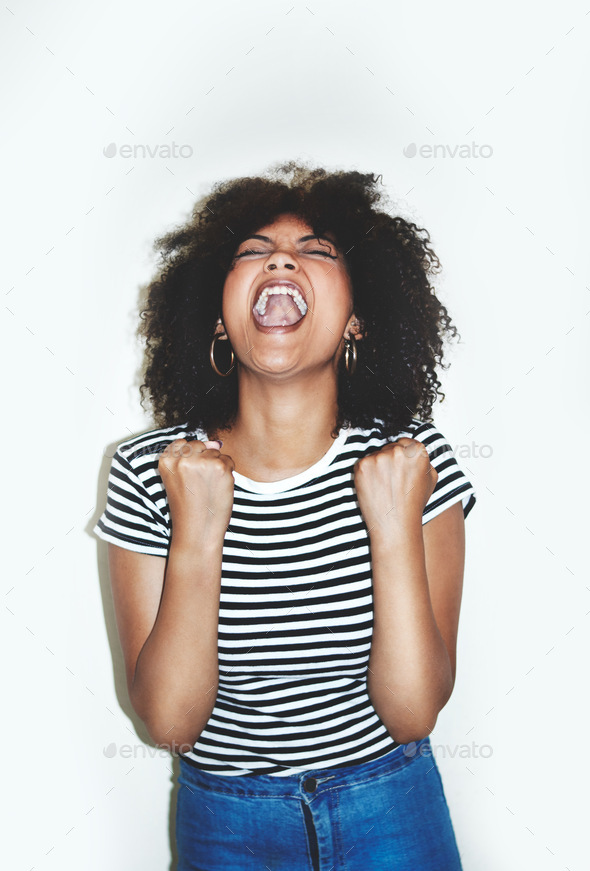 An explosion of rage. Studio shot of a young woman screaming in anger ...