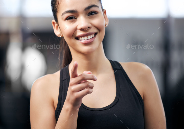 Portrait of a fit young woman pointing while working out at the gym ...