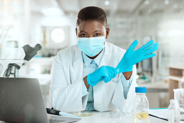 Shot of a young scientist sitting alone in her laboratory and putting ...