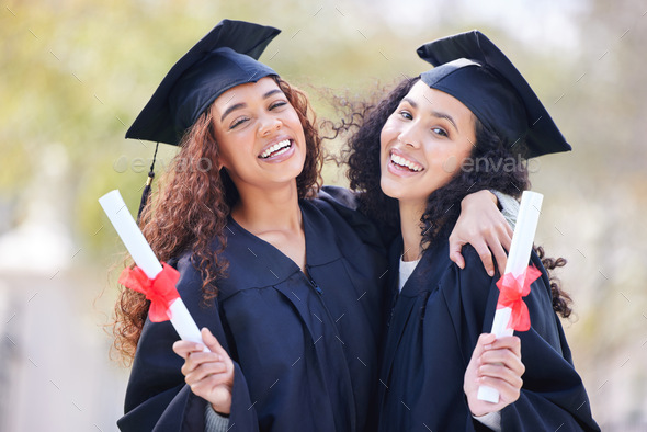Portrait of two young women holding their diplomas on graduation day ...