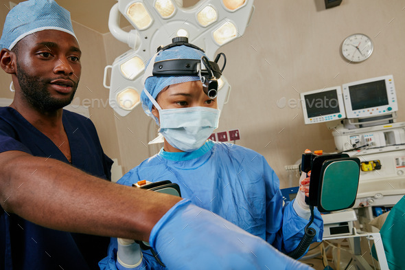 Shot of a surgeon using a defibrillator on a patient during surgery ...