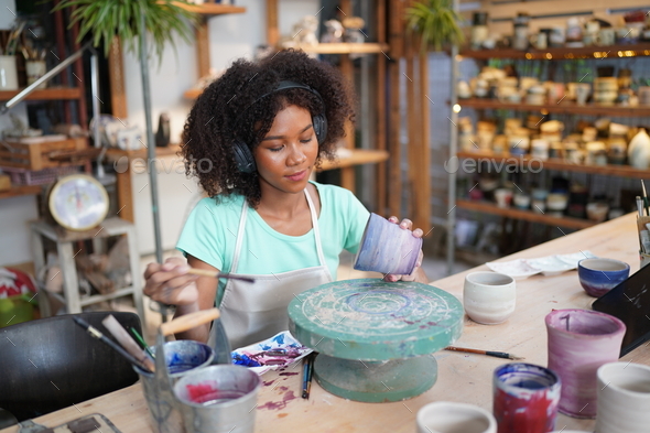 Ceramic artist painting exterior surface of pottery piece Stock Photo ...