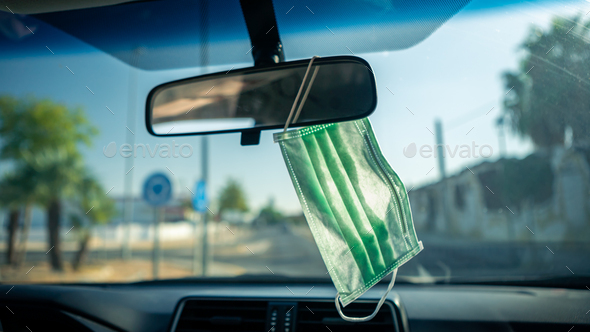 Hygienic masks hanging on rearview mirror inside of car whit sunlight ...