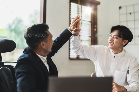 Smiling male colleagues celebrate shared success. Working together with ...