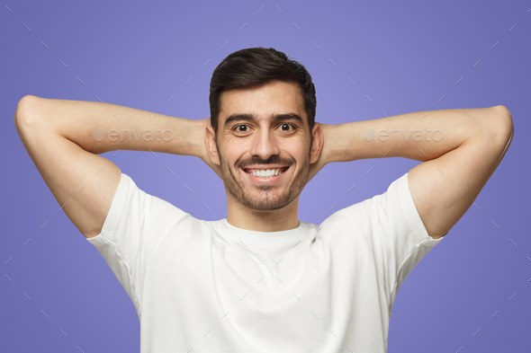 Man standing isolated on purple background with arms behind head ...