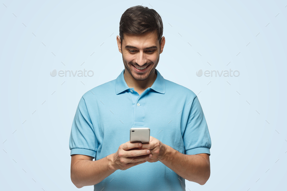 Man looking at screen of his phone with smile, browsing web pages ...