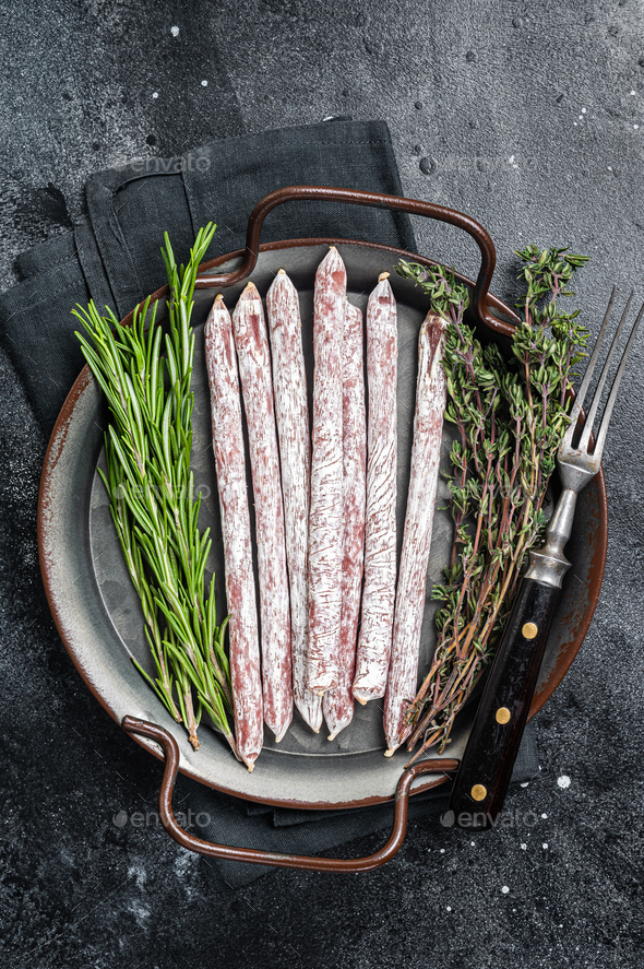 Spanish tapa mini fuet sausage with herbs. Black background. Top view ...