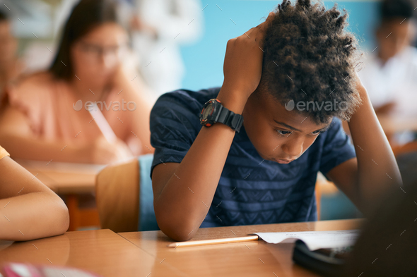 Uncertain African American schoolboy having exam during a class in the ...