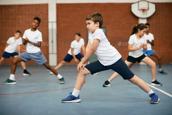 Elementary student and his friends warming up during PE class at school ...