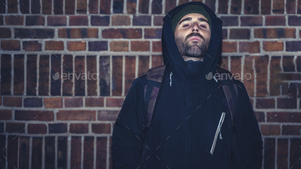 Urban portrait, of a young man, wearing a jacket and hood over his head ...