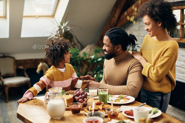 Happy African American parents talking to their daughter at dining ...