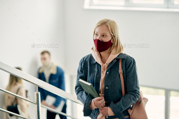 Smiling college student wearing face mask while going to lecture during ...