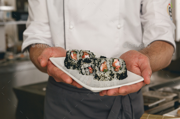 Close up of chef of japanies restaurant showing plate with sushi ...