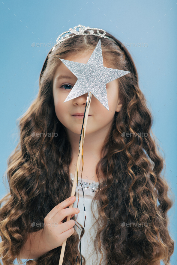 Indoor shot of good looking small female child with long curly hair ...