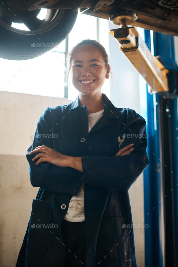 Shot of a female mechanic posing with her arms crossed in an auto ...