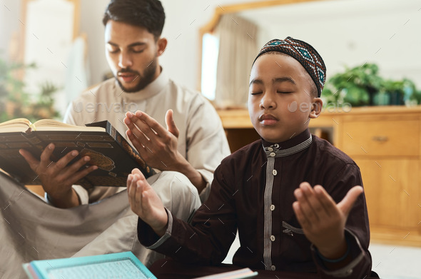 Shot of a young muslim man and his son reading in the lounge at home ...