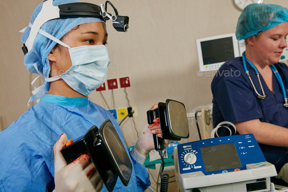 Shot of a surgeon using a defibrillator on a patient during surgery ...