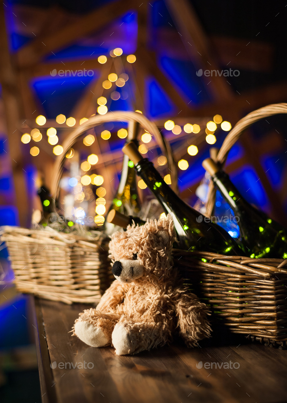 Teddy bear, champagne bottle with Christmas basket, gold garlands on ...