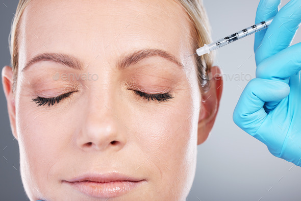 Studio shot of an attractive mature woman receiving a botox injection ...