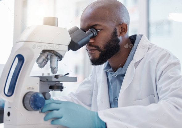 Success is a science. Shot of a young scientist using a microscope in a ...
