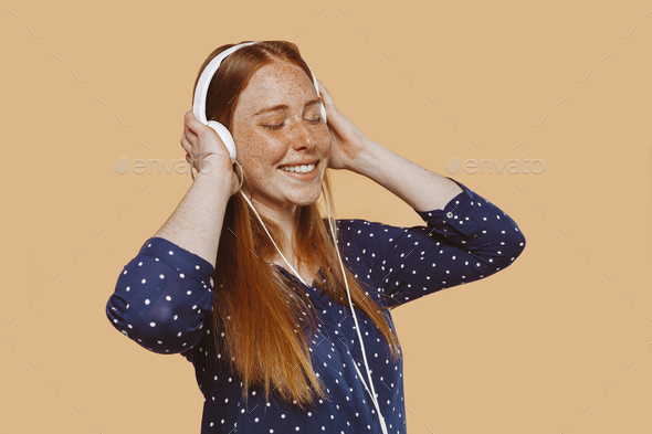 Red head woman with freckles listen music with earphones Stock Photo by ...