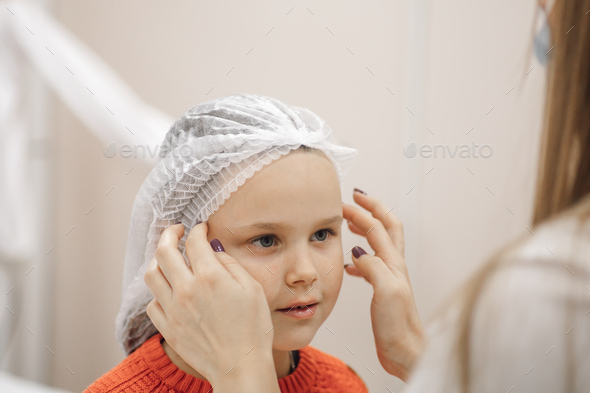 close-up of doctor hands putting white disposable medical cap on head ...