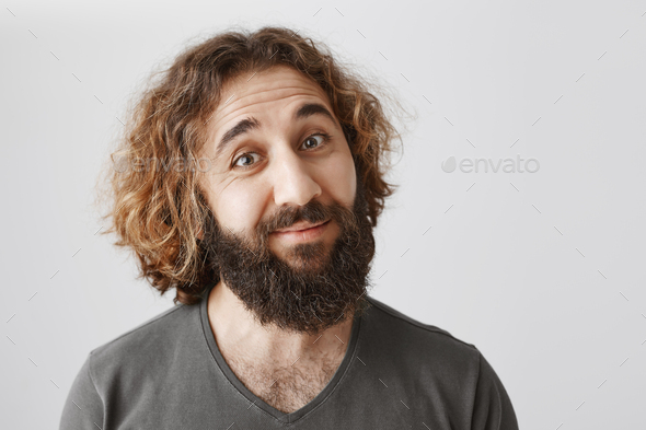 Indoor portrait of doubtful polite eastern guy with beard tilting and ...