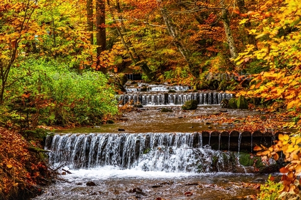 Narrow stream falling down mountain slope in autumn forest Stock Photo ...