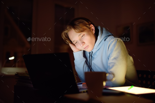 Tired teenager napping while studying at home with laptop and tablet pc ...