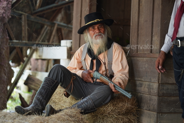 Brutal cowboy with revolver, gunfight on ranch, rural background. Stock ...