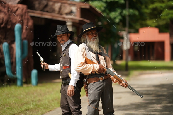 Brutal cowboy with revolver, gunfight on ranch, rural background. Stock ...