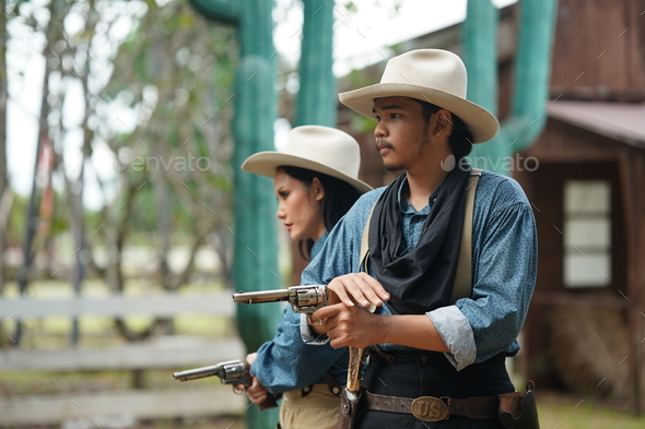Brutal cowboy with revolver, gunfight on ranch, rural background. Stock ...