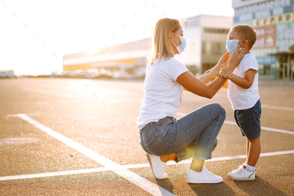 Mother puts on her baby sterile medical mask at sunset during pandemic ...