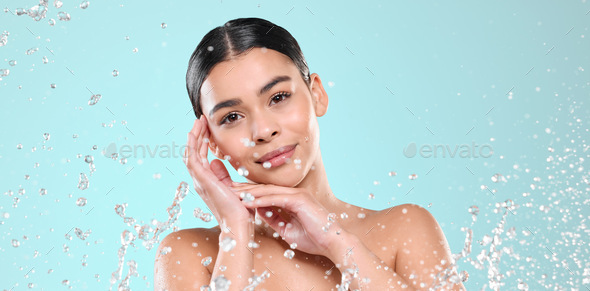 Shot of a beautiful young woman being splashed with water against a ...