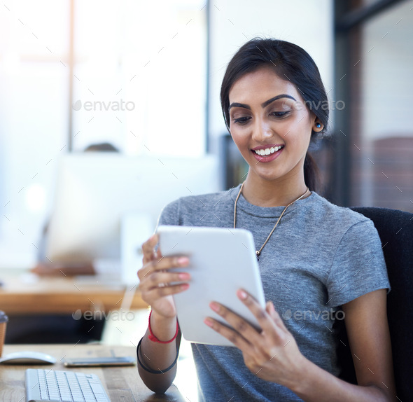 Shot of a young businesswoman using a digital tablet at her work desk ...