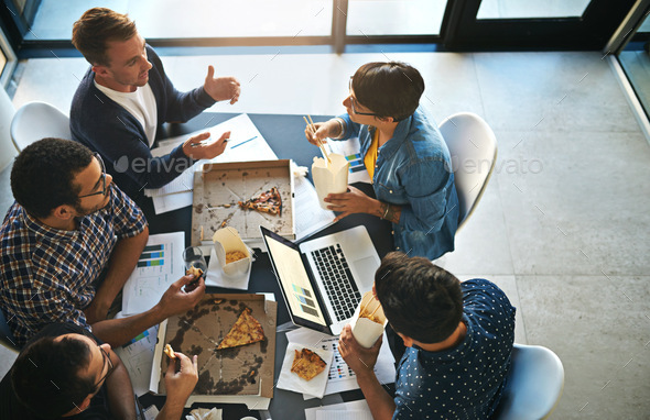 Meeting over a meal. Shot of a group of colleagues eating while having ...