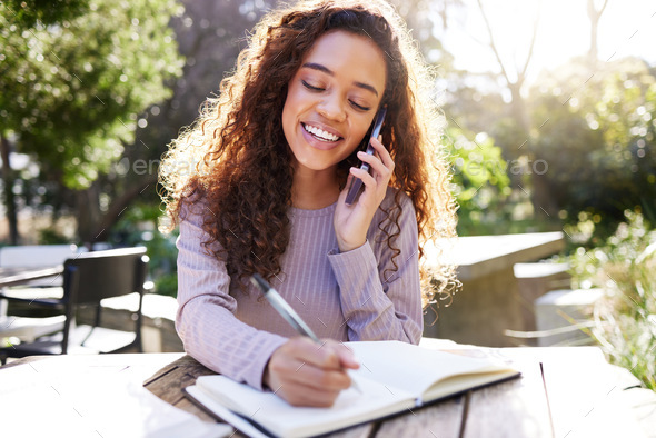 Shot of a young female student using a phone while studying at a cafe ...