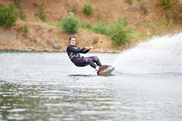 Hes a professional. Sporty young guy out wakeboarding on the lake ...