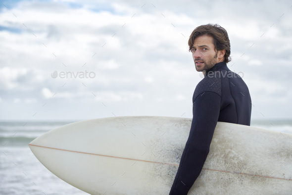 Hitting the beach. A surfer with his surfboard at the beach. Stock ...