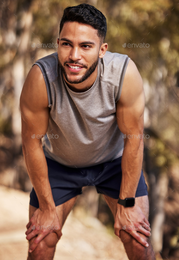 Shot of a handsome young man taking a moment to catch his breath during ...