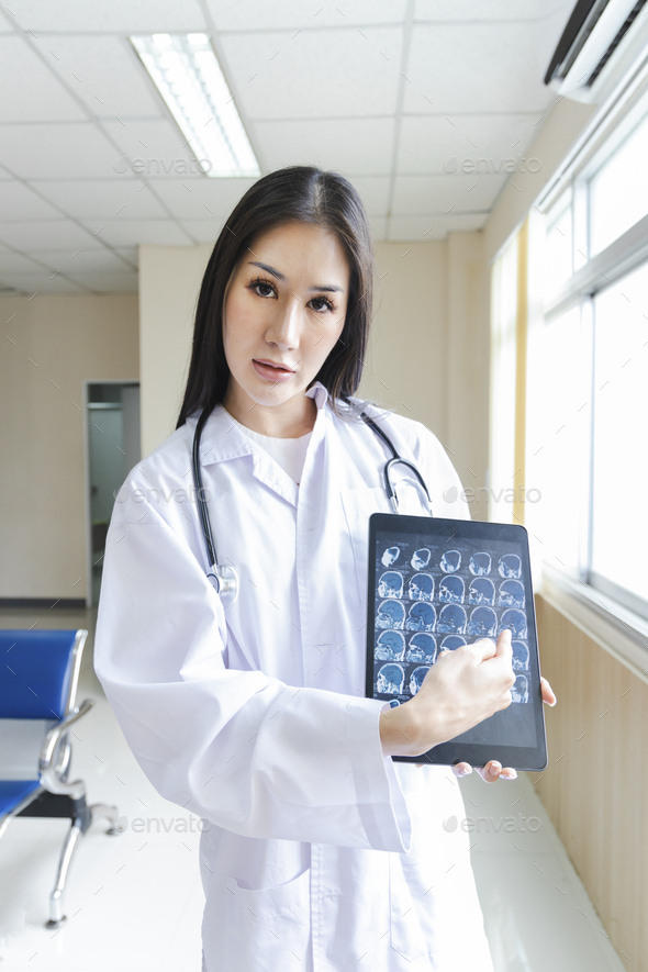 smart female doctor holding tablet to show X-Ray picture and standing ...