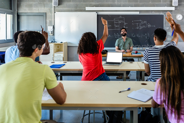 Group of young students raising hands in class on lecture Stock Photo ...