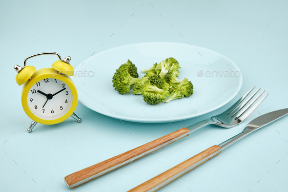 Intermittent fasting, diet, lunch time concept. Yellow alarm clock ...