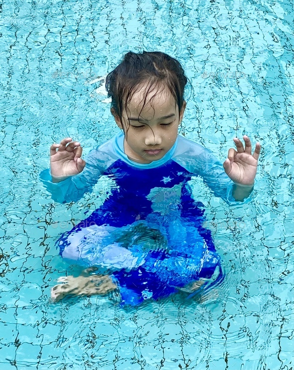 Little girl practicing yoga in the swimming pool Stock Photo by lolodean