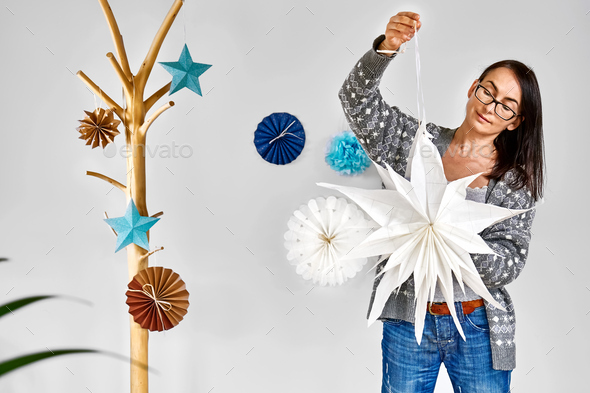 Woman decorating home with stars, fans and snowflakes made of recycled ...