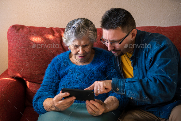 Grandma holding smartphone to call with her grandson sitting on living ...
