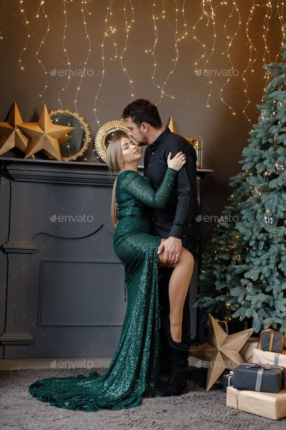 Romantic couple standing near Christmas tree wearing magnificent ...