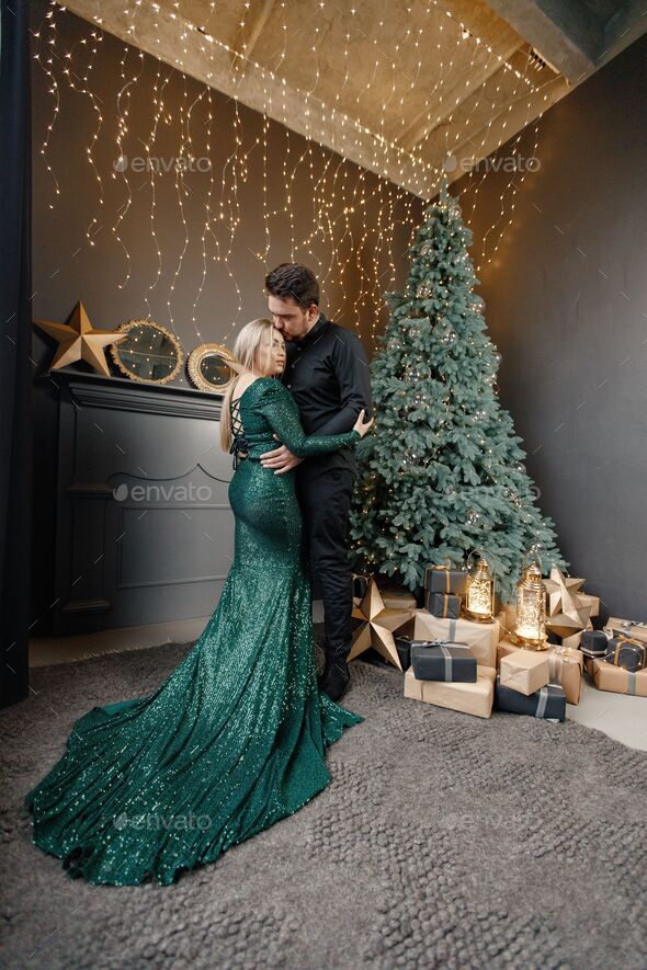 Romantic couple standing near Christmas tree wearing magnificent ...